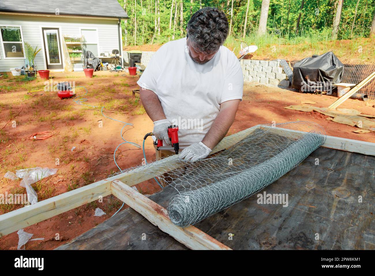 Worker nailing a metal mesh to wooden frame Stock Photo - Alamy