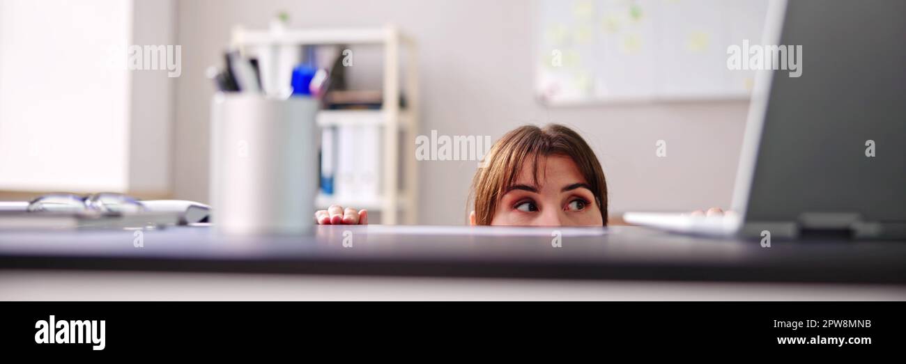 Scared Woman Hiding Behind Chair And Under Desk Stock Photo - Alamy