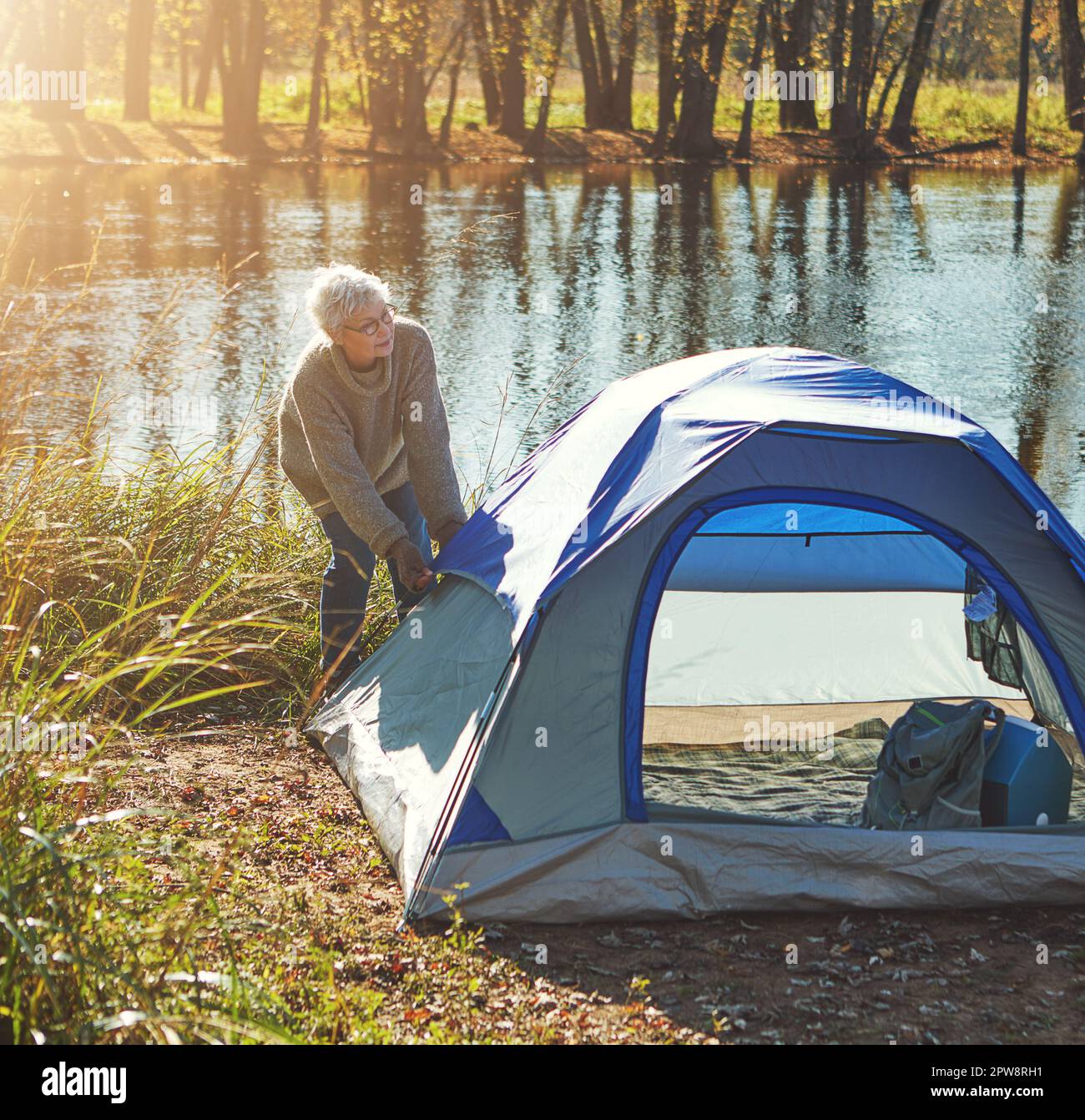 Ensuring her tent is sturdy and cosy. a senior woman setting up a tent ...
