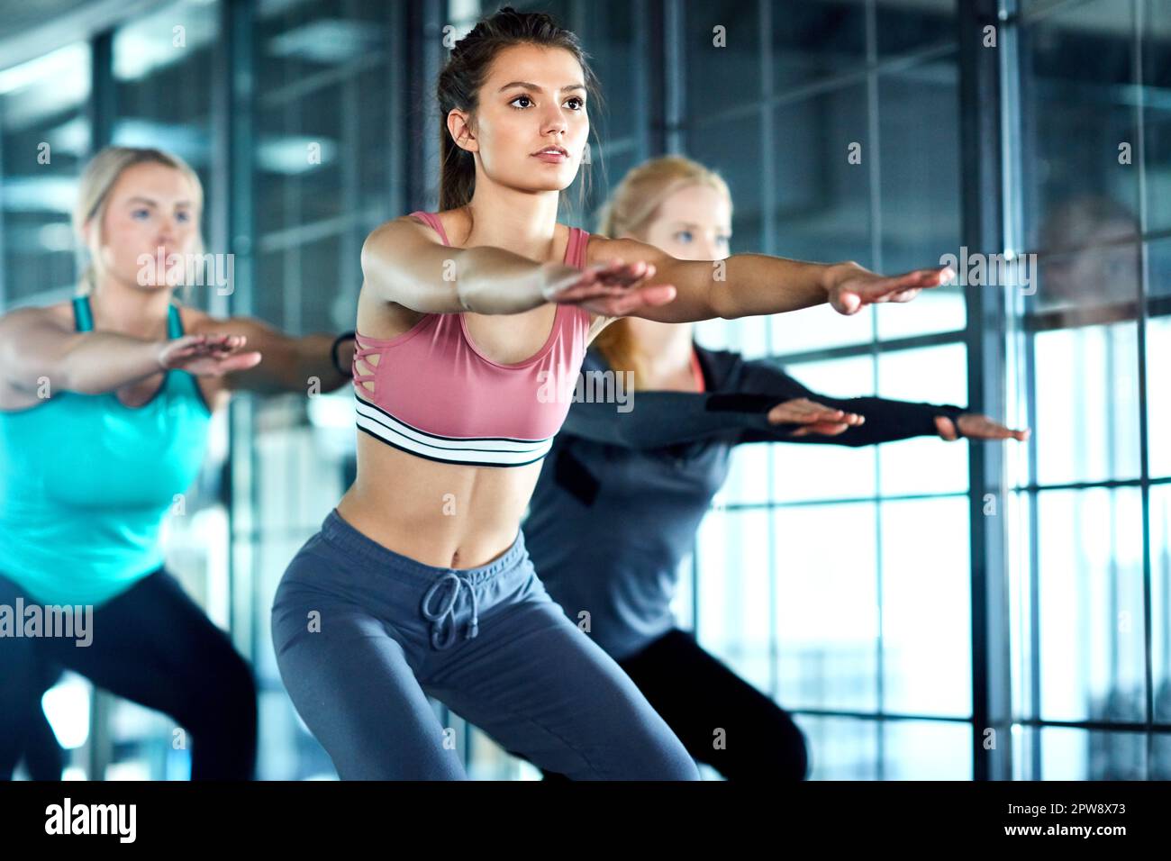 Motivated by her peers. three attractive young women working out ...
