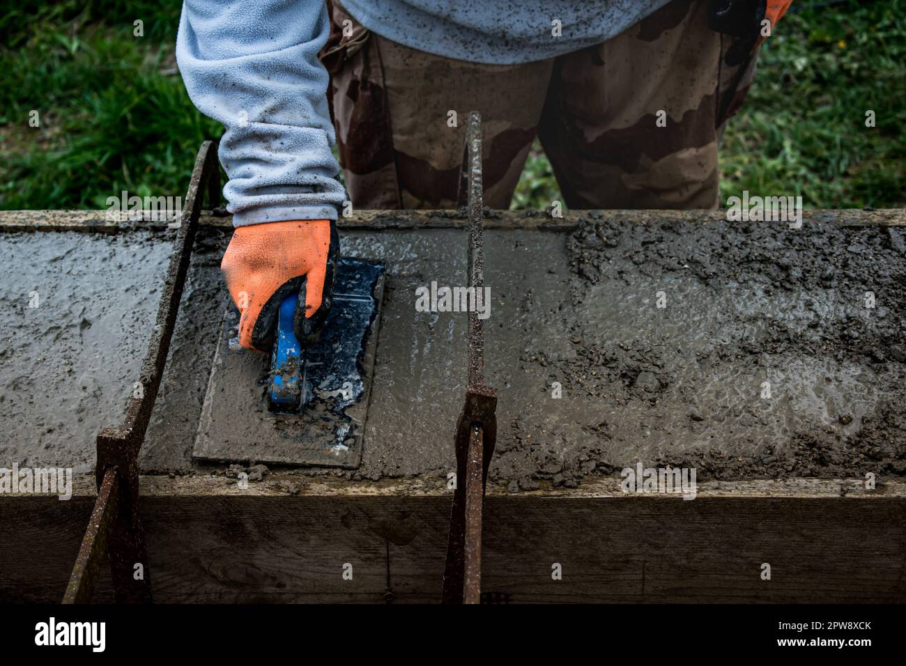 Bricklayer spreading concrete with a trowel and level to build a wall ...