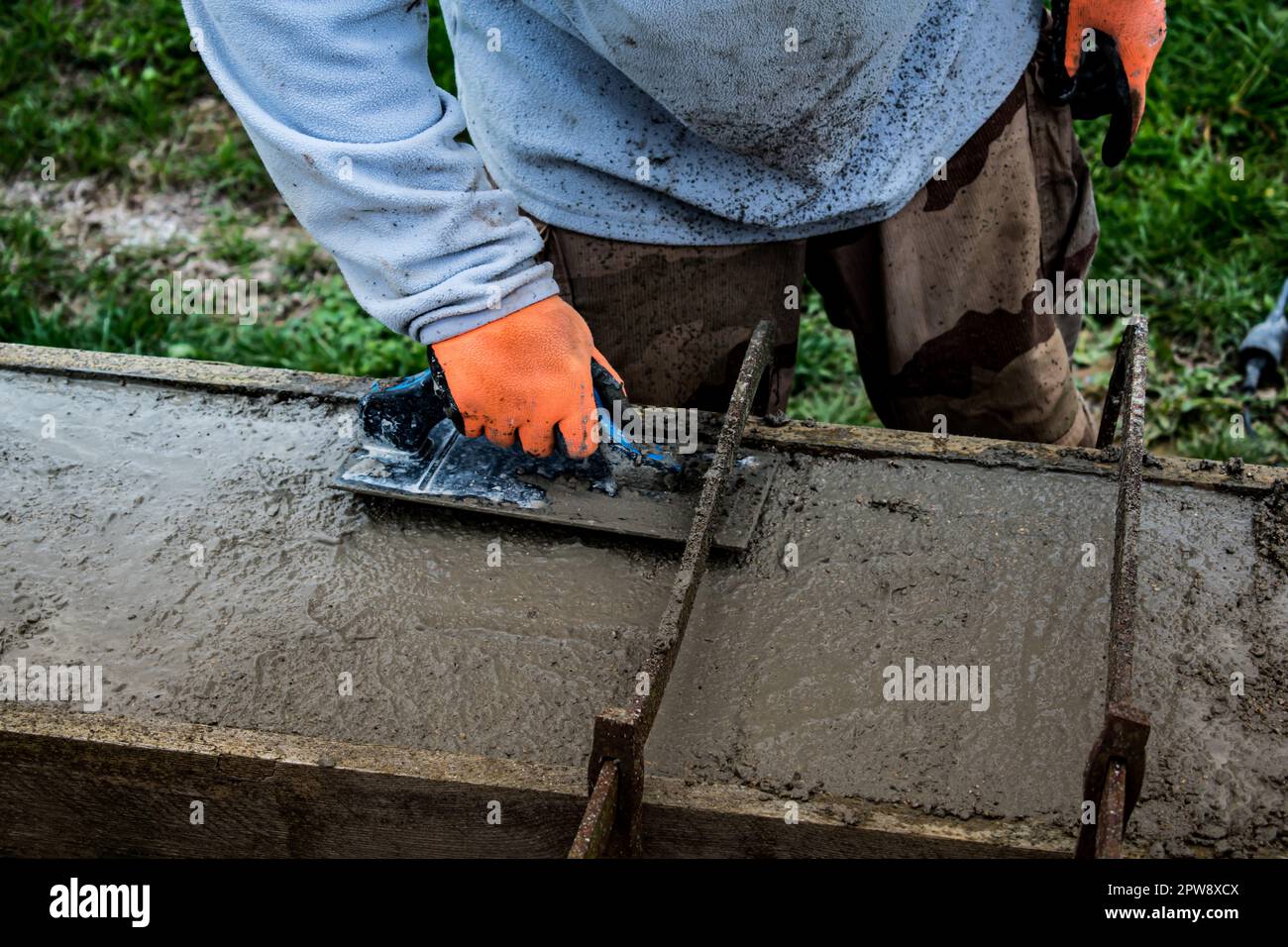 Bricklayer spreading concrete with a trowel and level to build a wall ...
