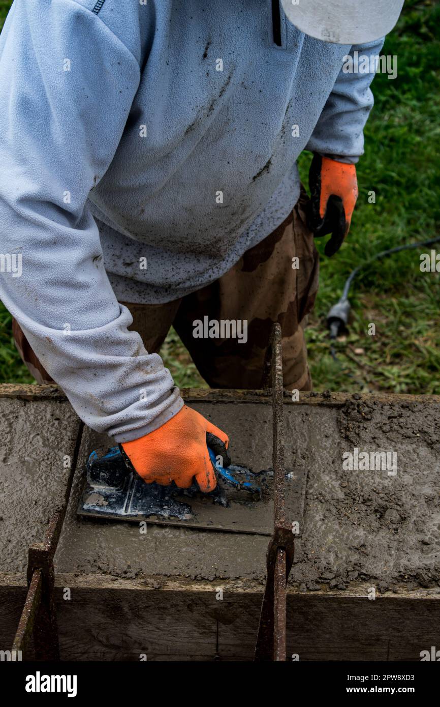 Bricklayer spreading concrete with a trowel and level to build a wall ...