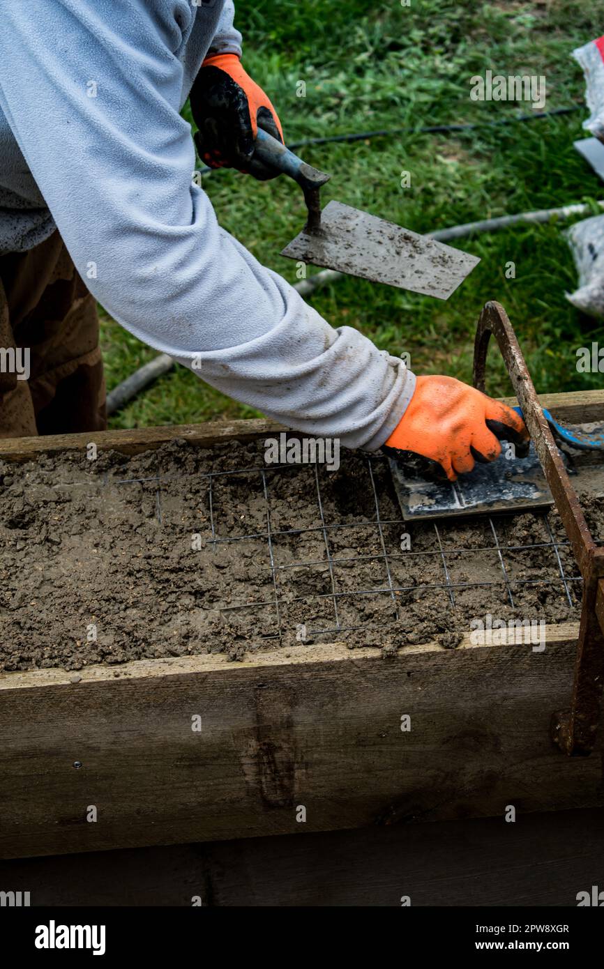 Bricklayer spreading concrete with a trowel and level to build a wall ...