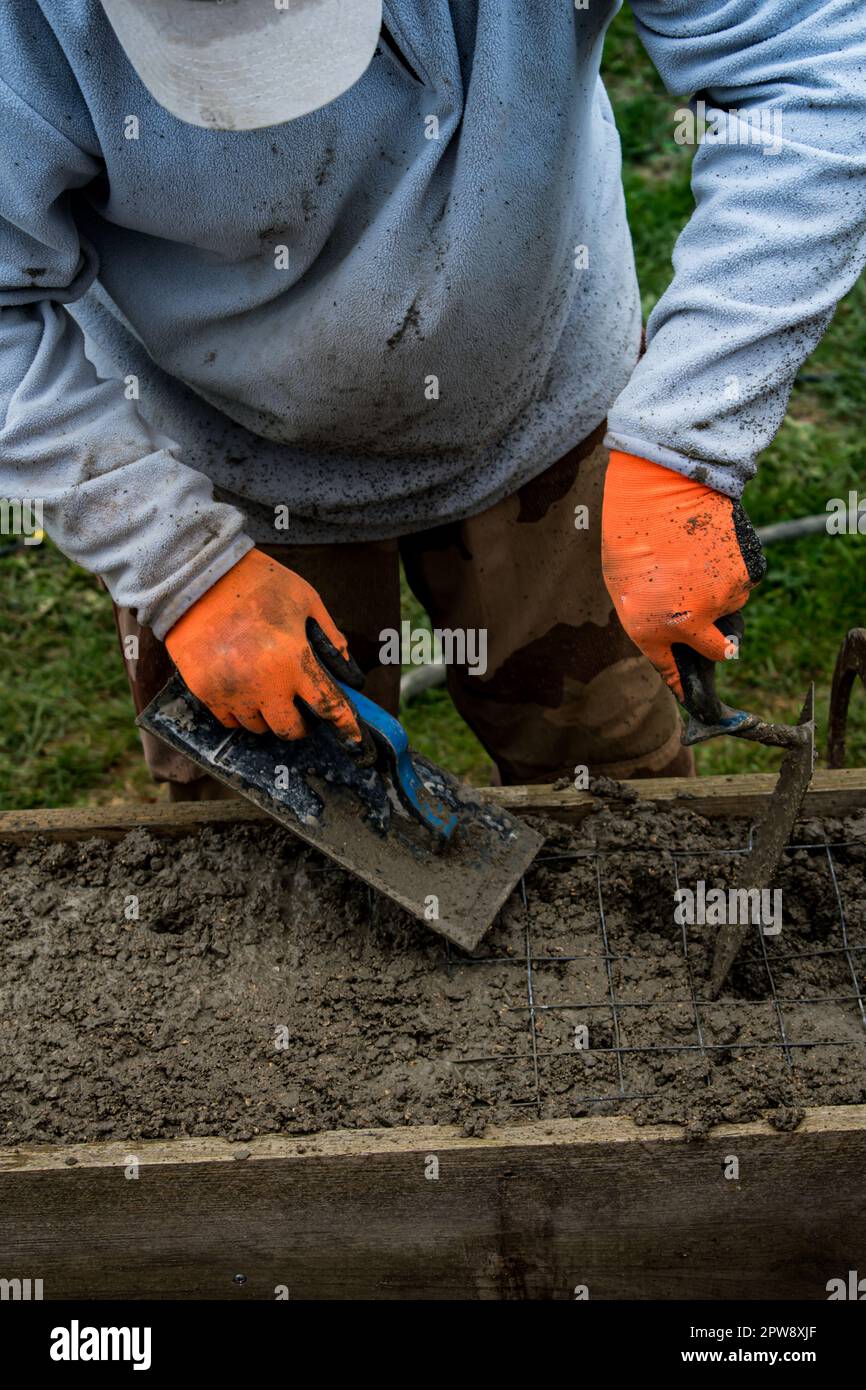Bricklayer spreading concrete with a trowel and level to build a wall ...