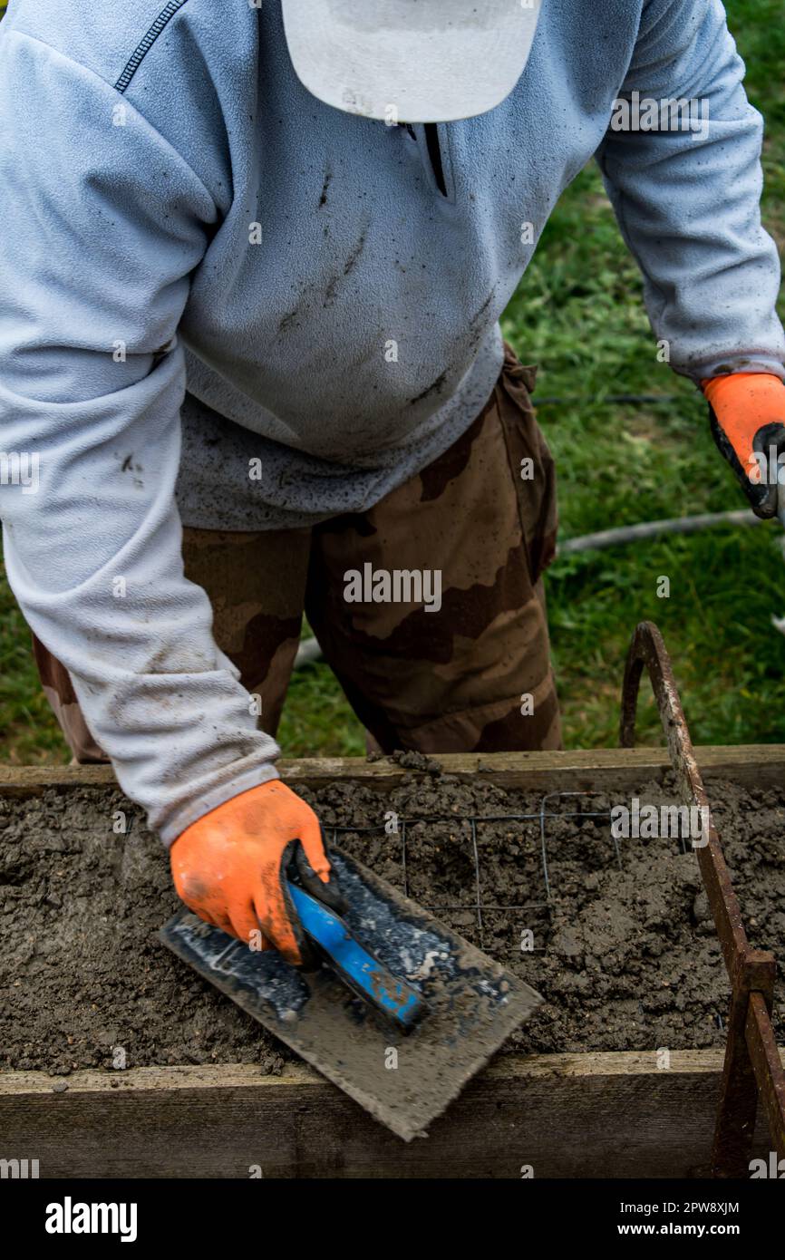 Bricklayer spreading concrete with a trowel and level to build a wall ...
