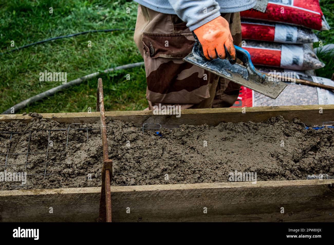 Bricklayer spreading concrete with a trowel and level to build a wall ...