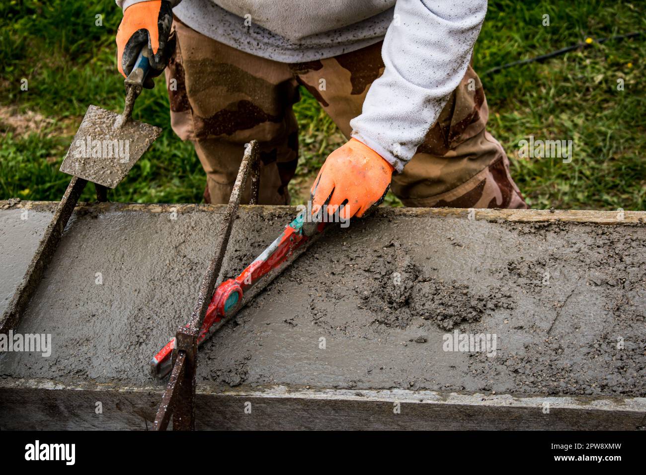 Bricklayer spreading concrete with a trowel and level to build a wall ...