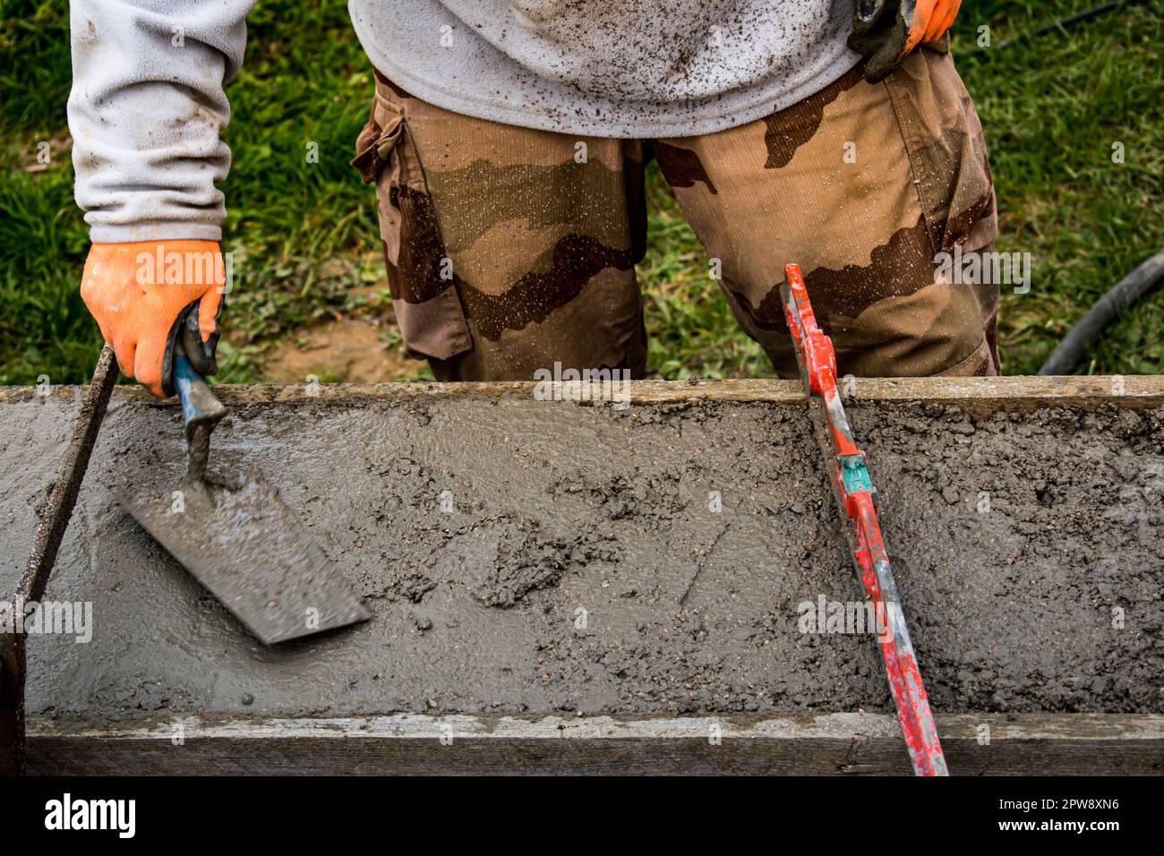 Bricklayer spreading concrete with a trowel and level to build a wall ...