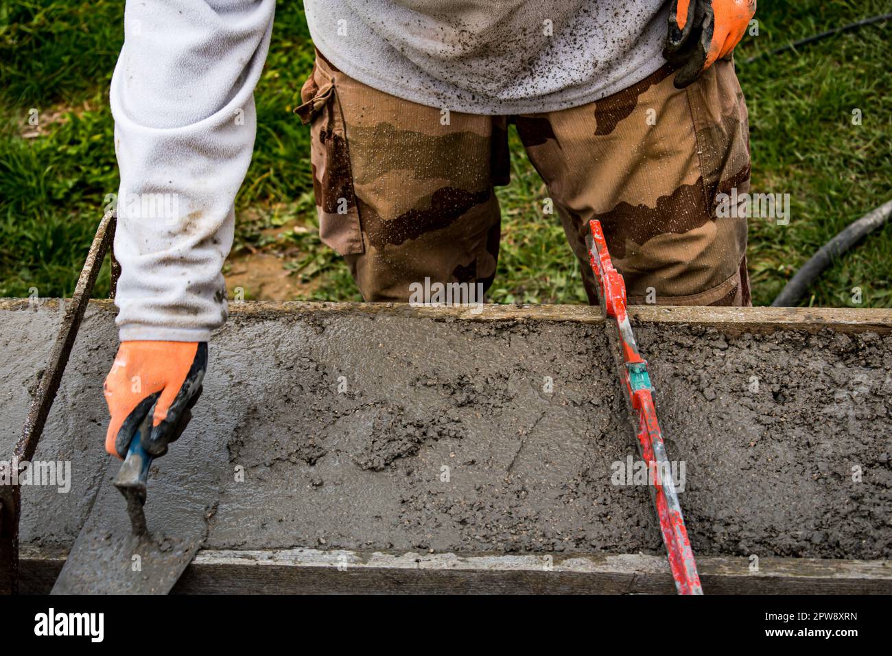 Bricklayer spreading concrete with a trowel and level to build a wall ...