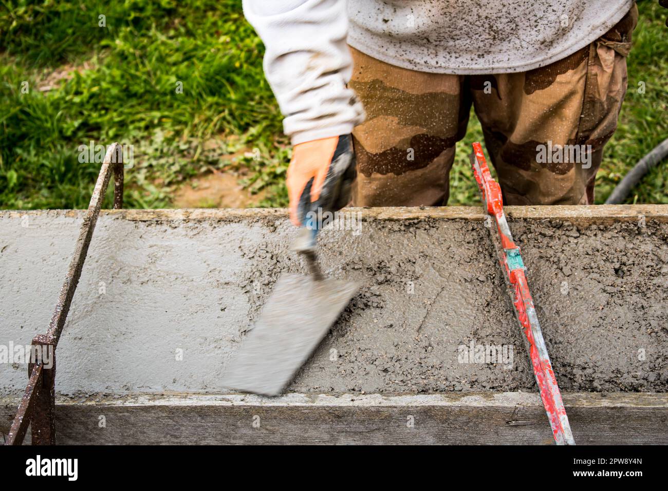 Bricklayer spreading concrete with a trowel and level to build a wall ...