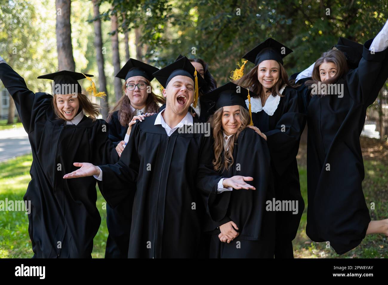 A group of graduates in robes congratulate each other on their ...