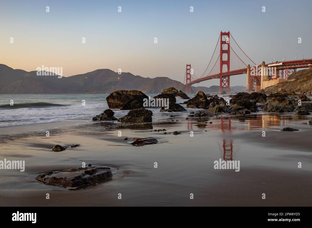 A picture of the Golden Gate Bridge and the Baker Beach rocks at sunset ...