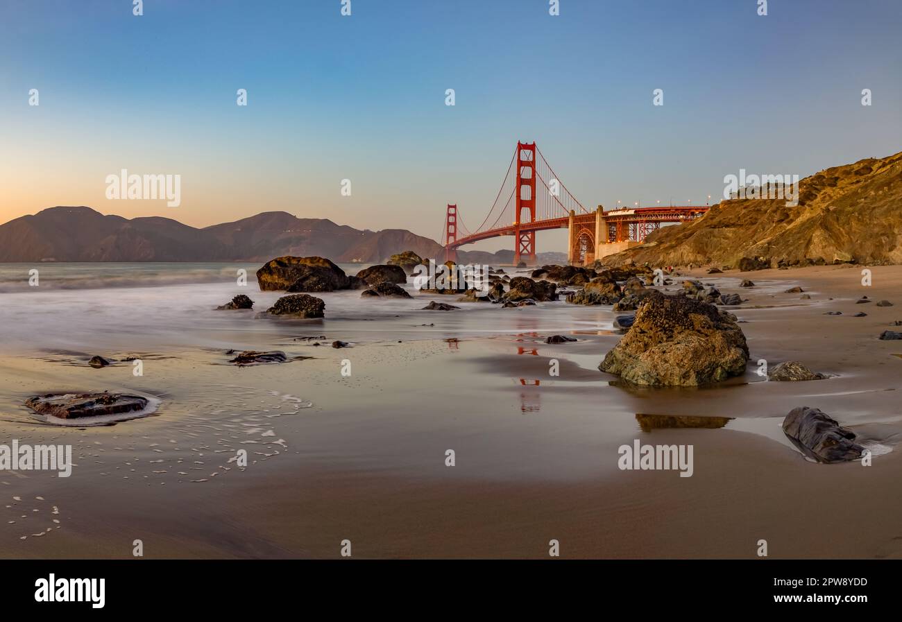 A picture of the Golden Gate Bridge and the Baker Beach rocks at sunset ...