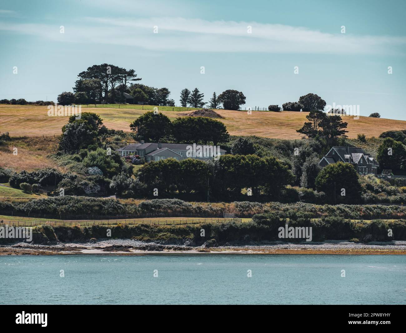 Houses, shore of the gulf of Ireland on a sunny summer day. Hilly Irish ...