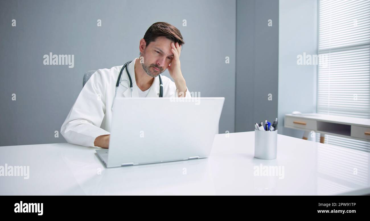 Frustrated Overworked Sad Doctor At Computer In Hospital Stock Photo ...
