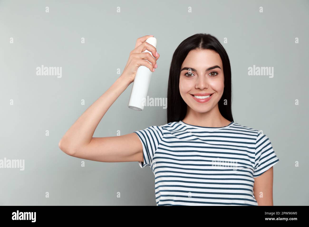 Woman applying dry shampoo onto her hair on light grey background Stock ...