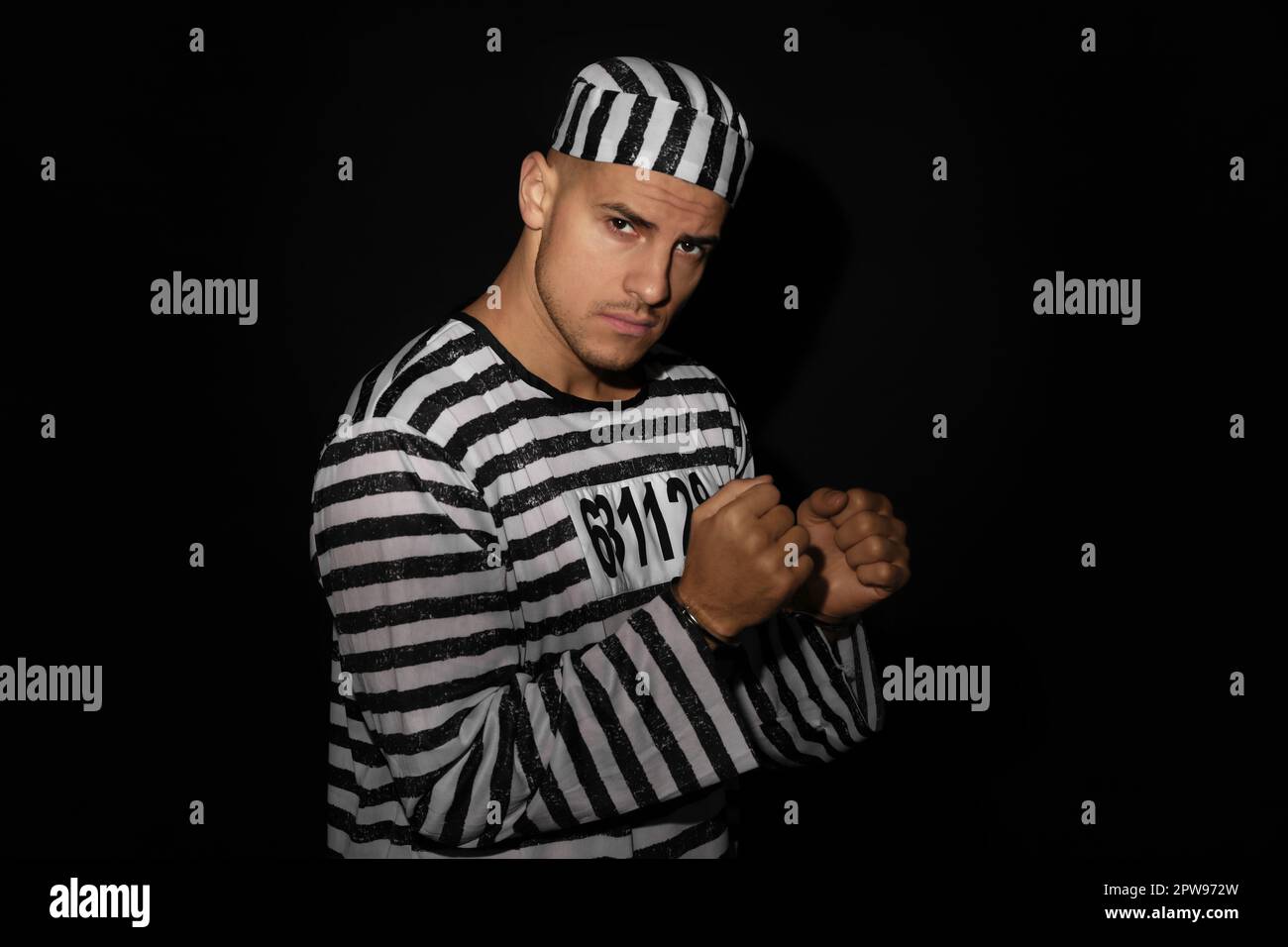 Prisoner in striped uniform with handcuffs on black background Stock ...