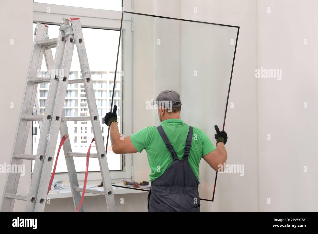 Worker in uniform holding double glazing window indoors, back view ...