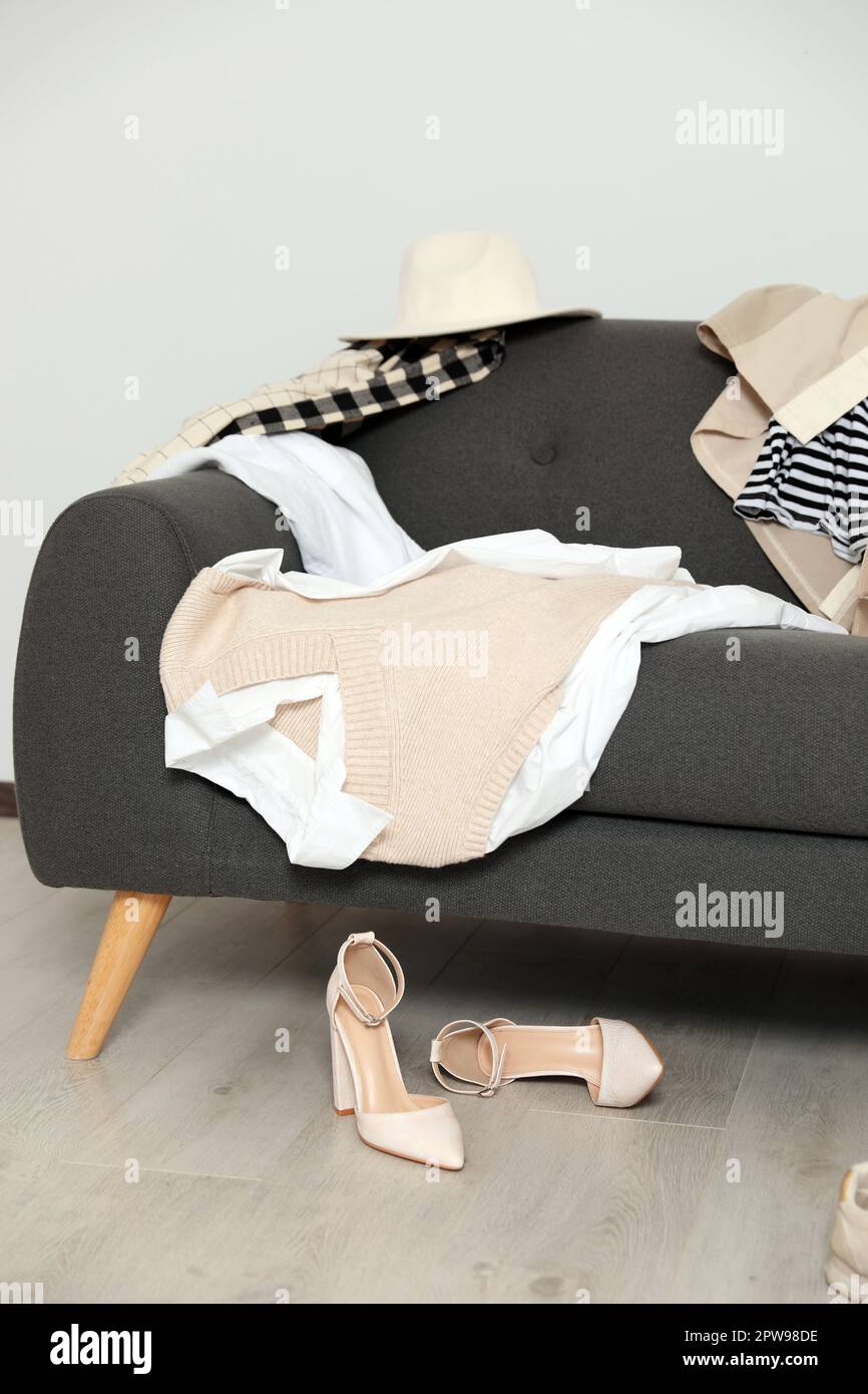 Messy pile of clothes on sofa and shoes in living room Stock Photo - Alamy