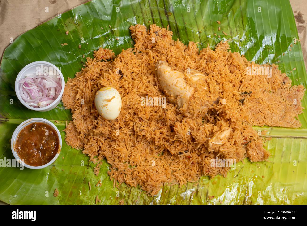 Hot chicken biryani with egg, raita and onion in banana leaf. A popular ...
