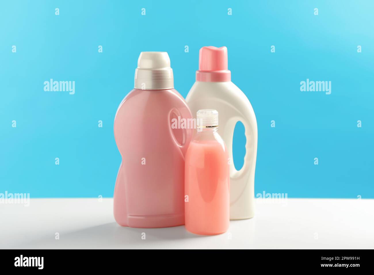Bottles of laundry detergents on white table Stock Photo - Alamy