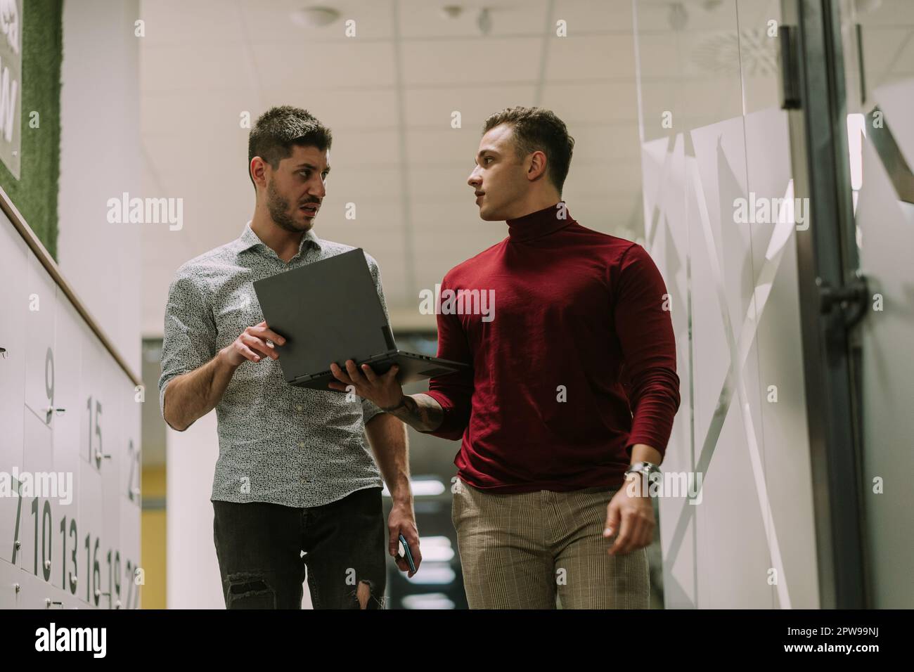 Good looking man trying to help his younger colleague with his daily ...