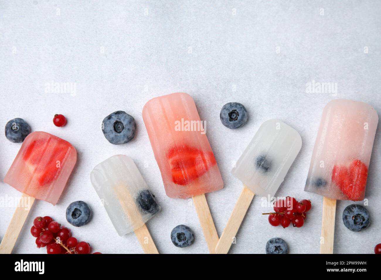 Flat lay composition with tasty berry ice pops on light table. Space ...
