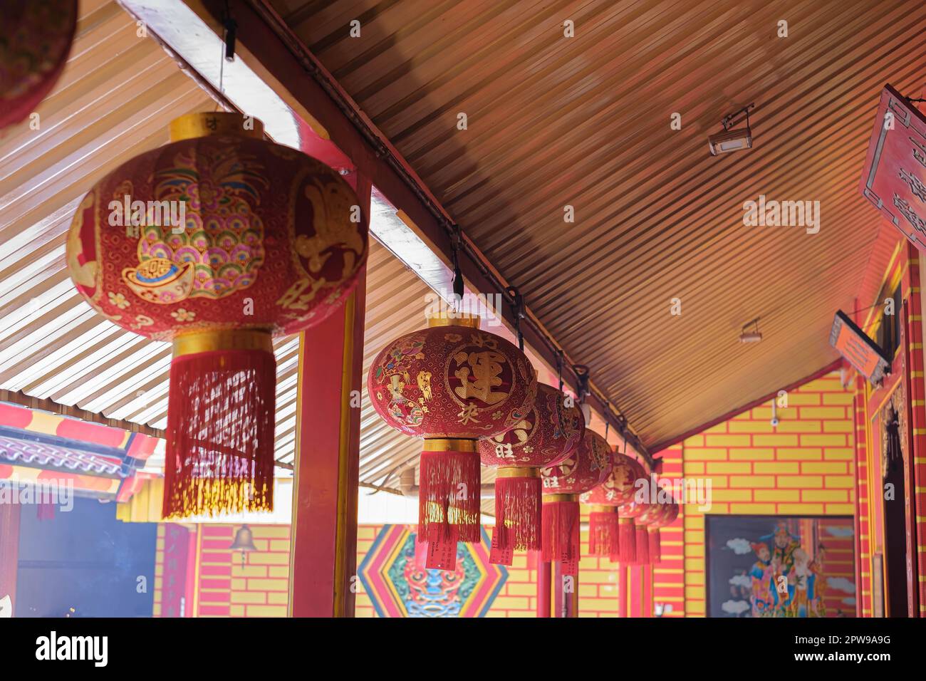 A row of typical red Chinese lanterns decorated with gold designs and trim with a colorful ...