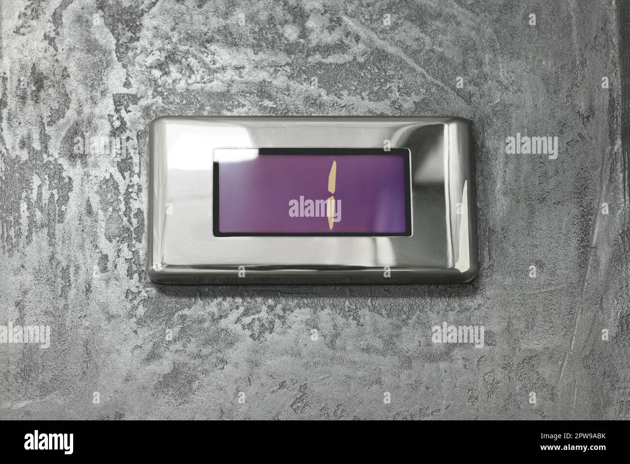 Elevator floor indicator with number one on grey textured wall, closeup ...