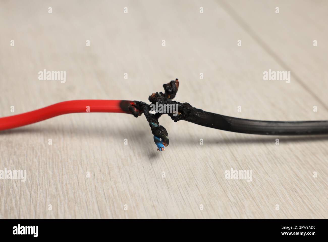 Burnt red wire on wooden floor, closeup. Electrical short circuit Stock ...