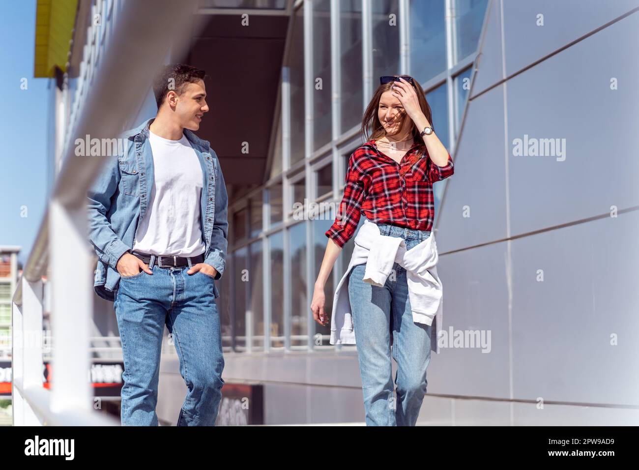 Cute couple walking in front the building while looking at eachother ...