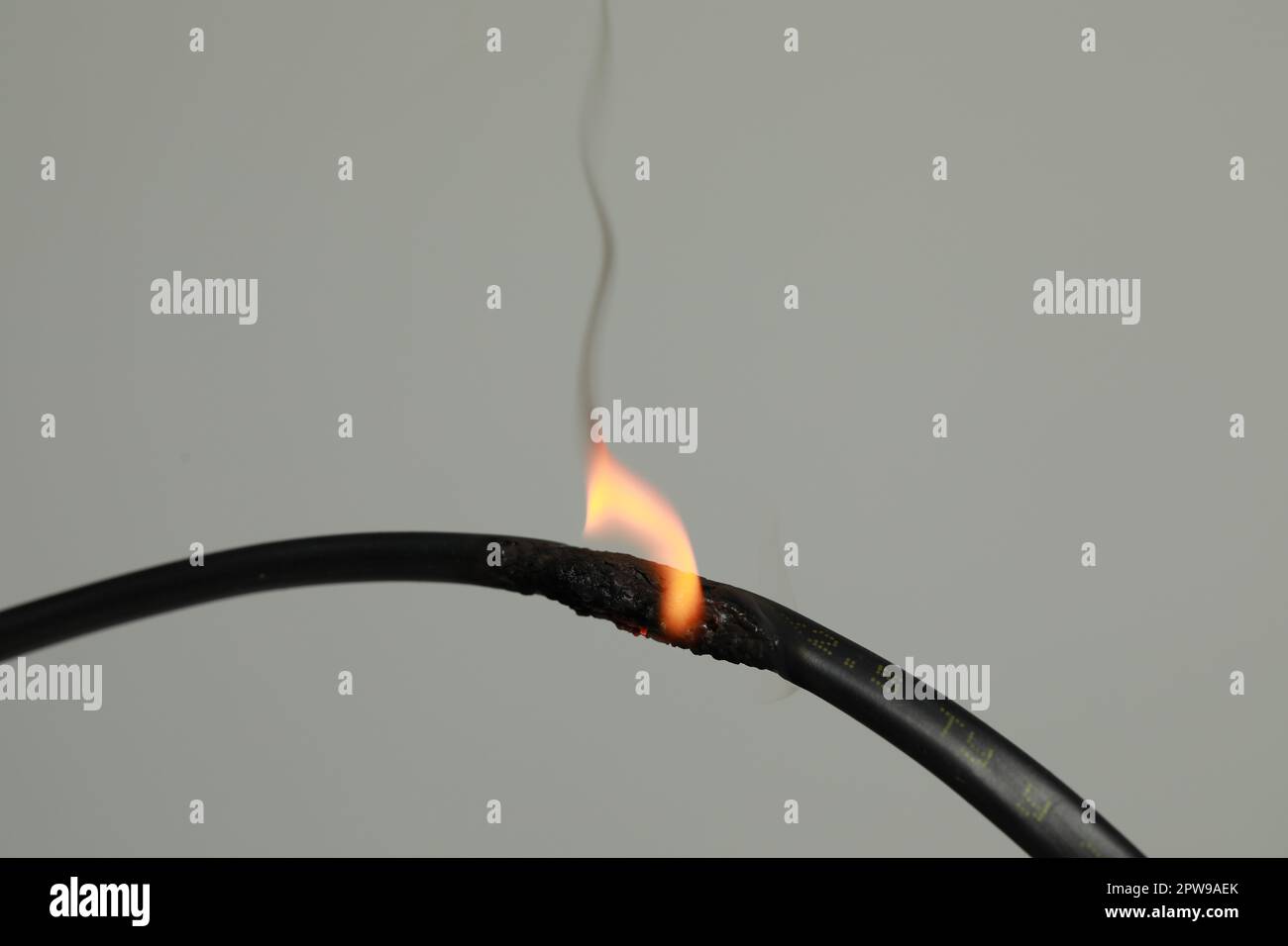 Inflamed black wire on grey background, closeup. Electrical short ...