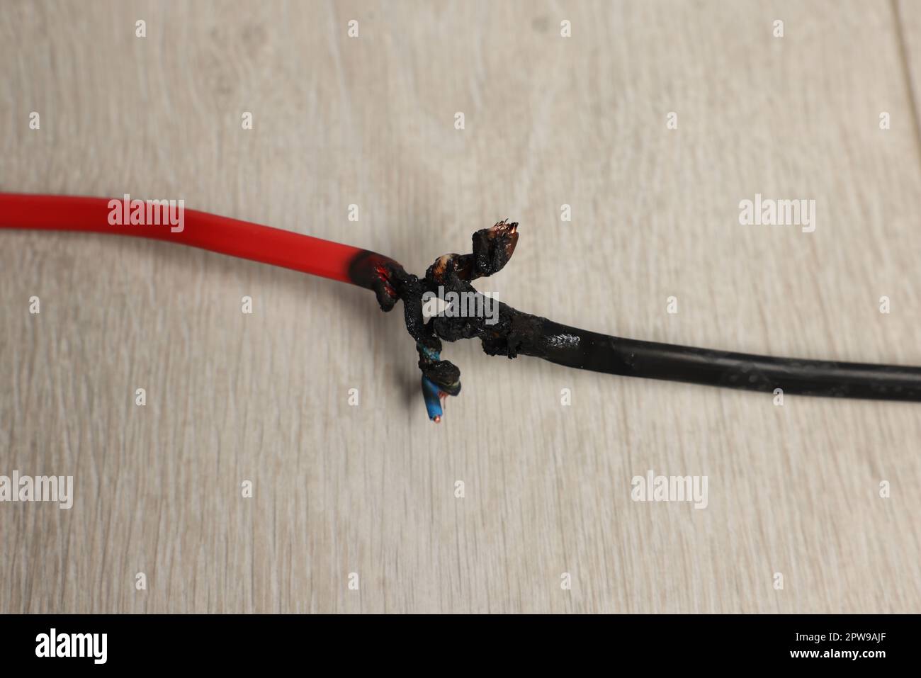 Burnt red wire on wooden floor, closeup. Electrical short circuit Stock ...