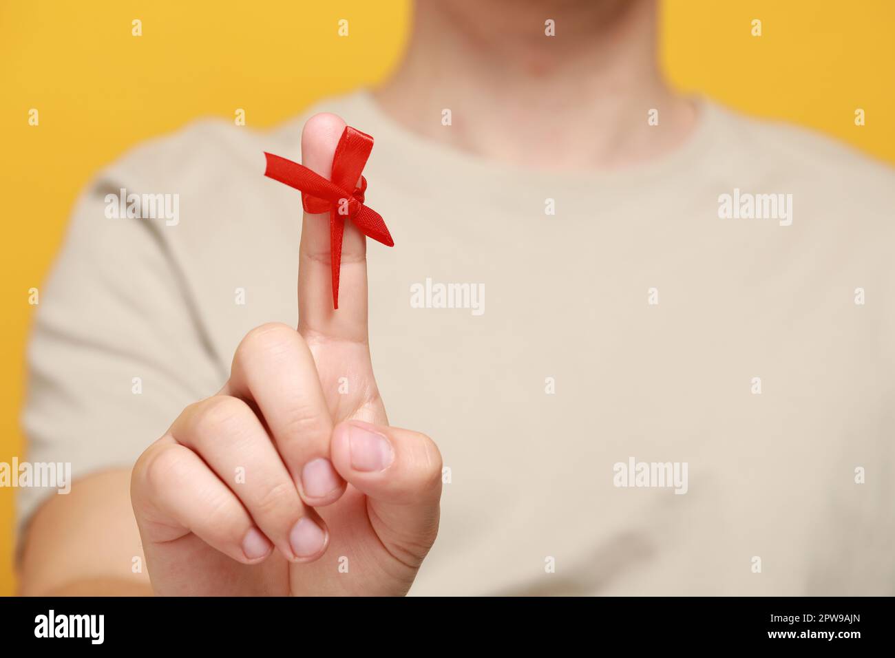 Man showing index finger with red tied bow as reminder against orange ...