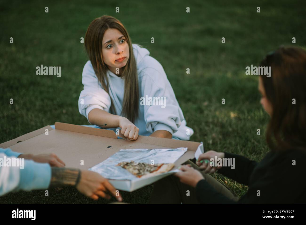 Friends fighting about the last pizza slice while sitting at the park ...