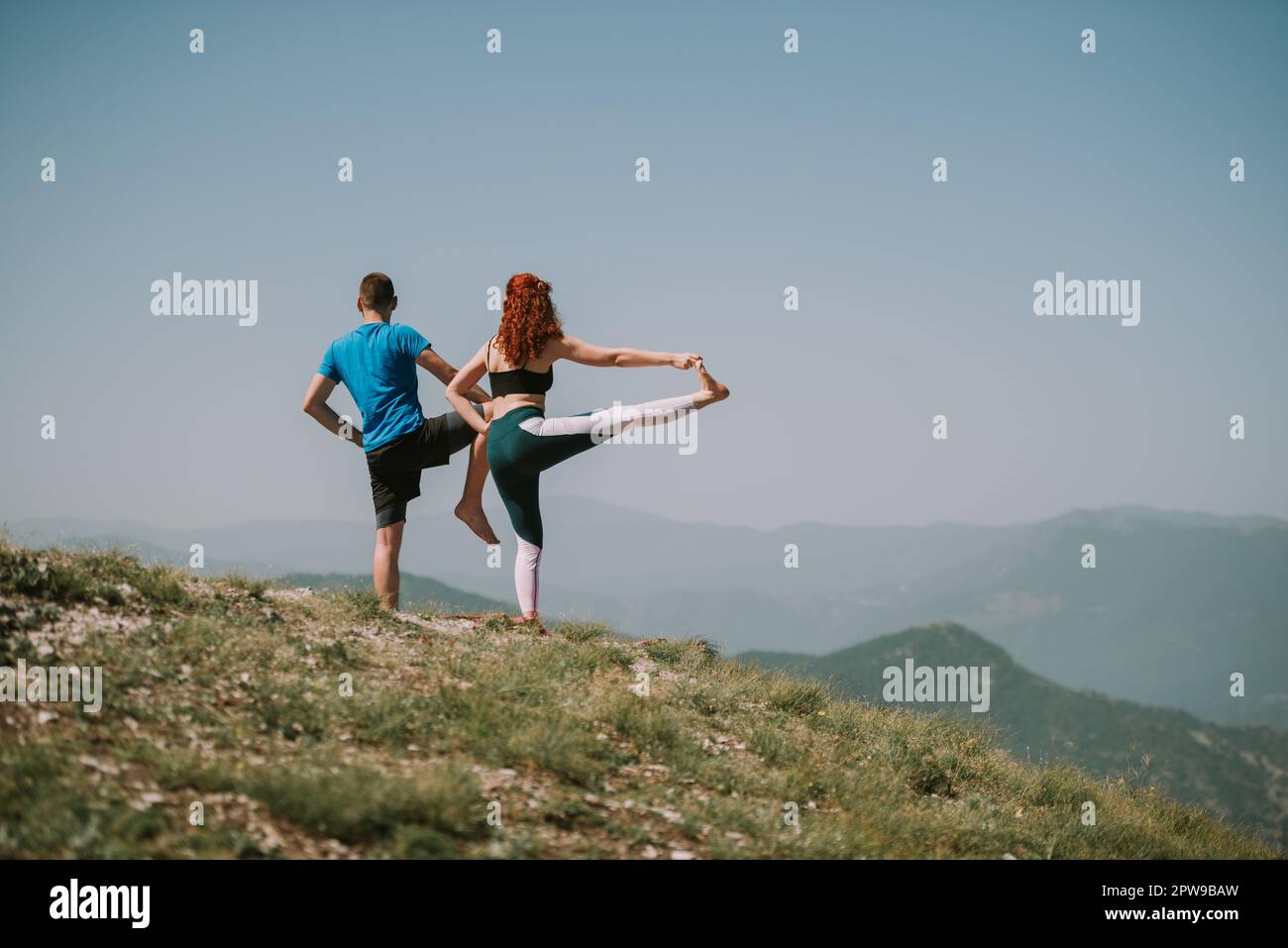 Strong yoga partners standing and streching their legs on the top of ...