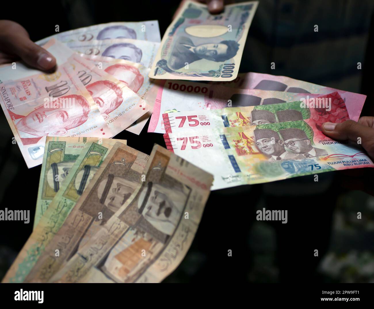 Asian child holding Indonesian rupiah, Singapore dollar, Saudi Arabia ...