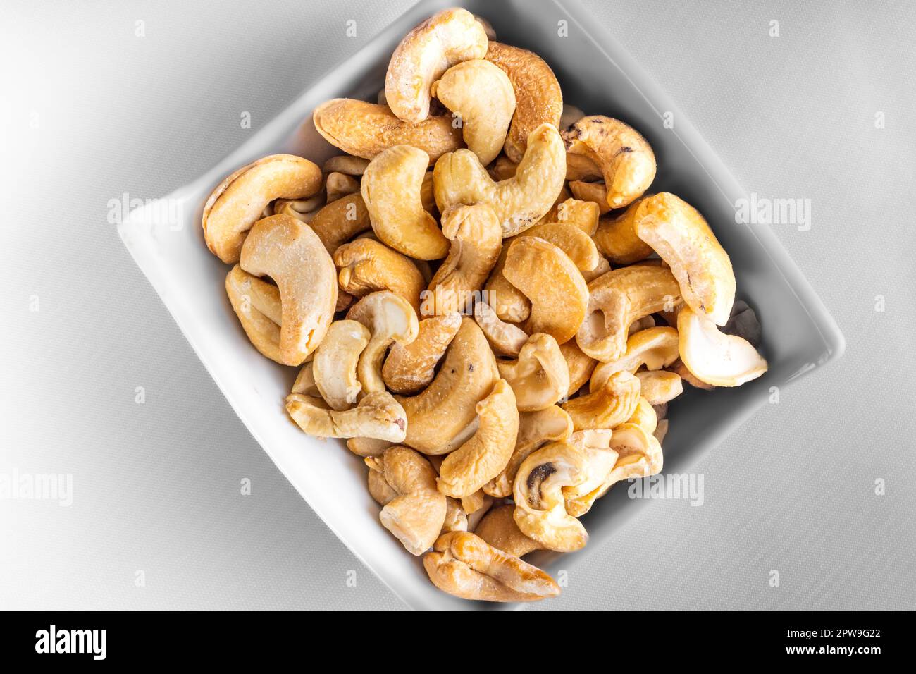 Cashew nuts in crockery pot on white background. Top view Stock Photo ...