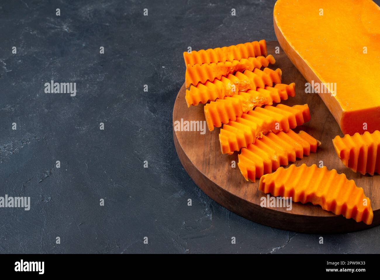 bottom view butternut squash chopped with zig-zag knife on wood board ...