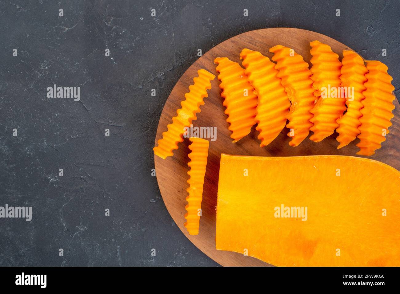top view butternut squash chopped with zig-zag knife on wood board on ...