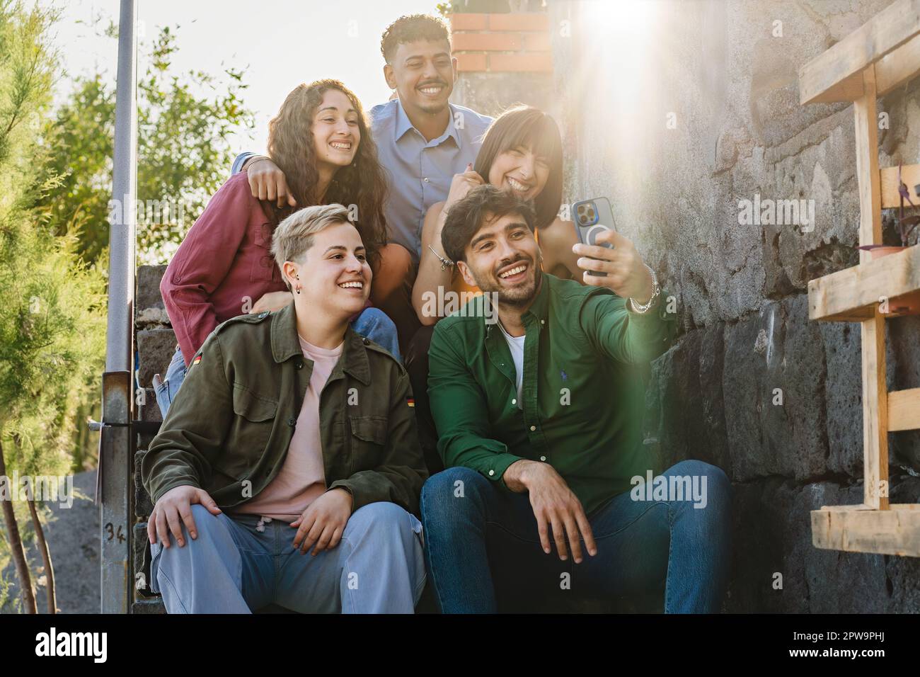 Young multiethnic friends taking a group selfie on seafront steps, enjoying their time together ...