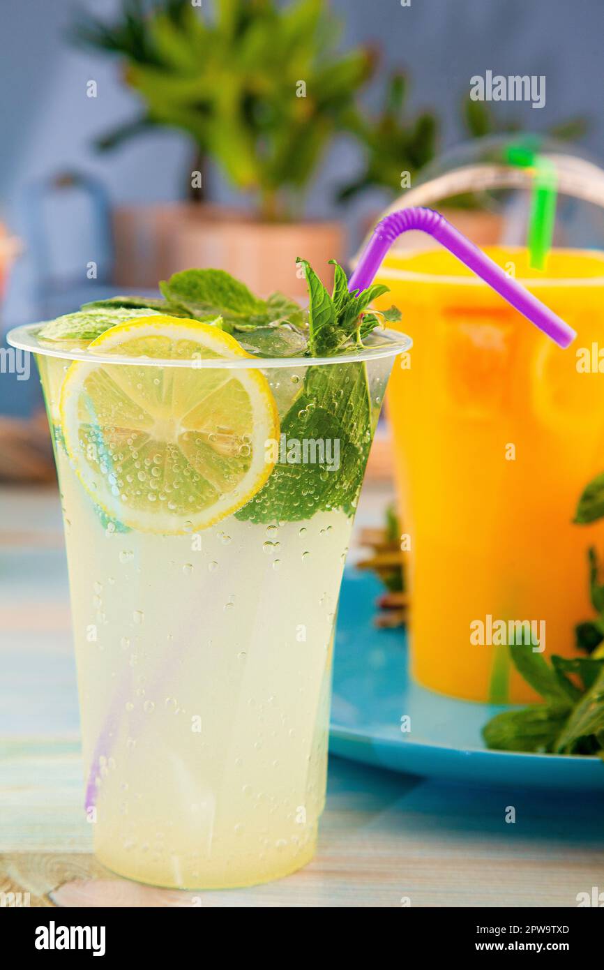 Summer mint lemon refreshing cocktail mojito with ice in plastic glass with straw. Carbonated ...