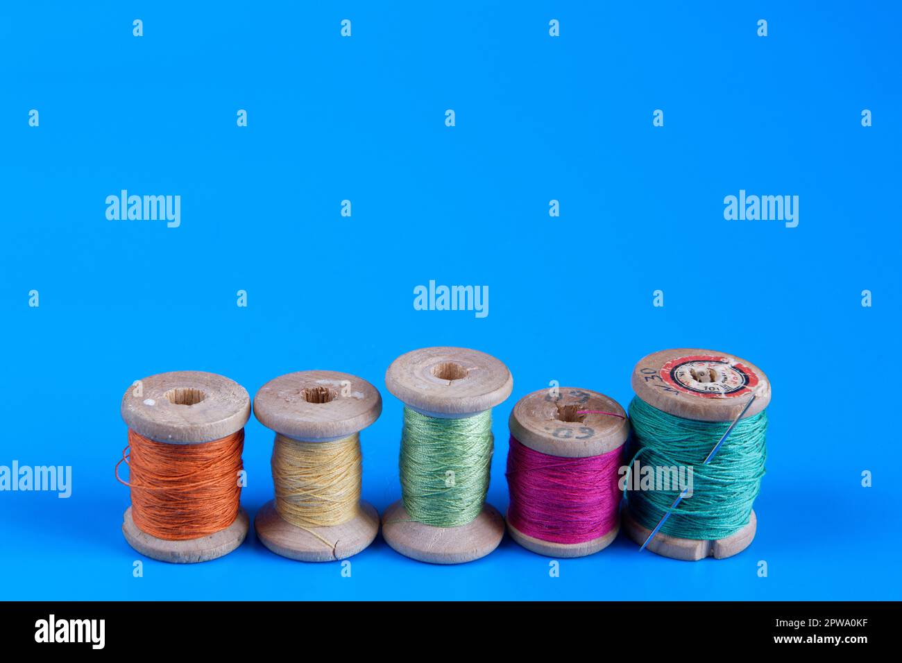 Old wooden reels of thread on blue background Stock Photo - Alamy