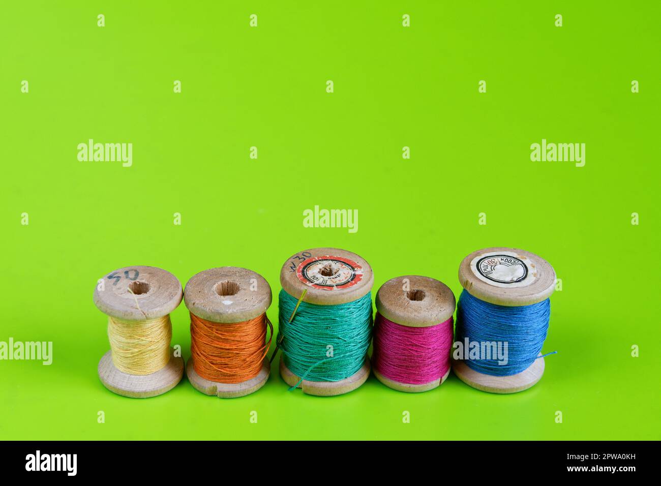Old wooden reels of thread on green background Stock Photo - Alamy
