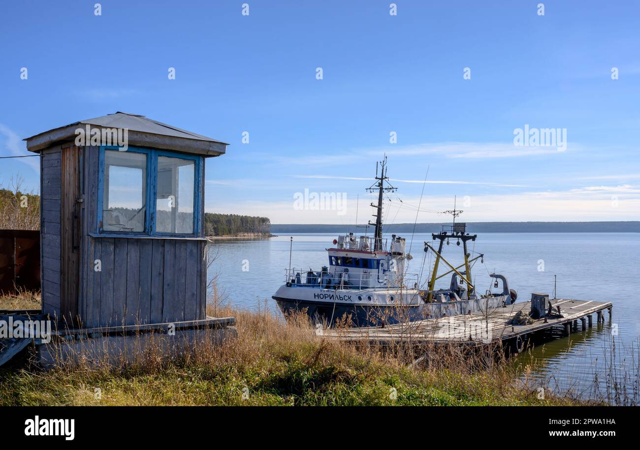 View of the Ob River bank with a wooden booth, a pier and a fishing ...