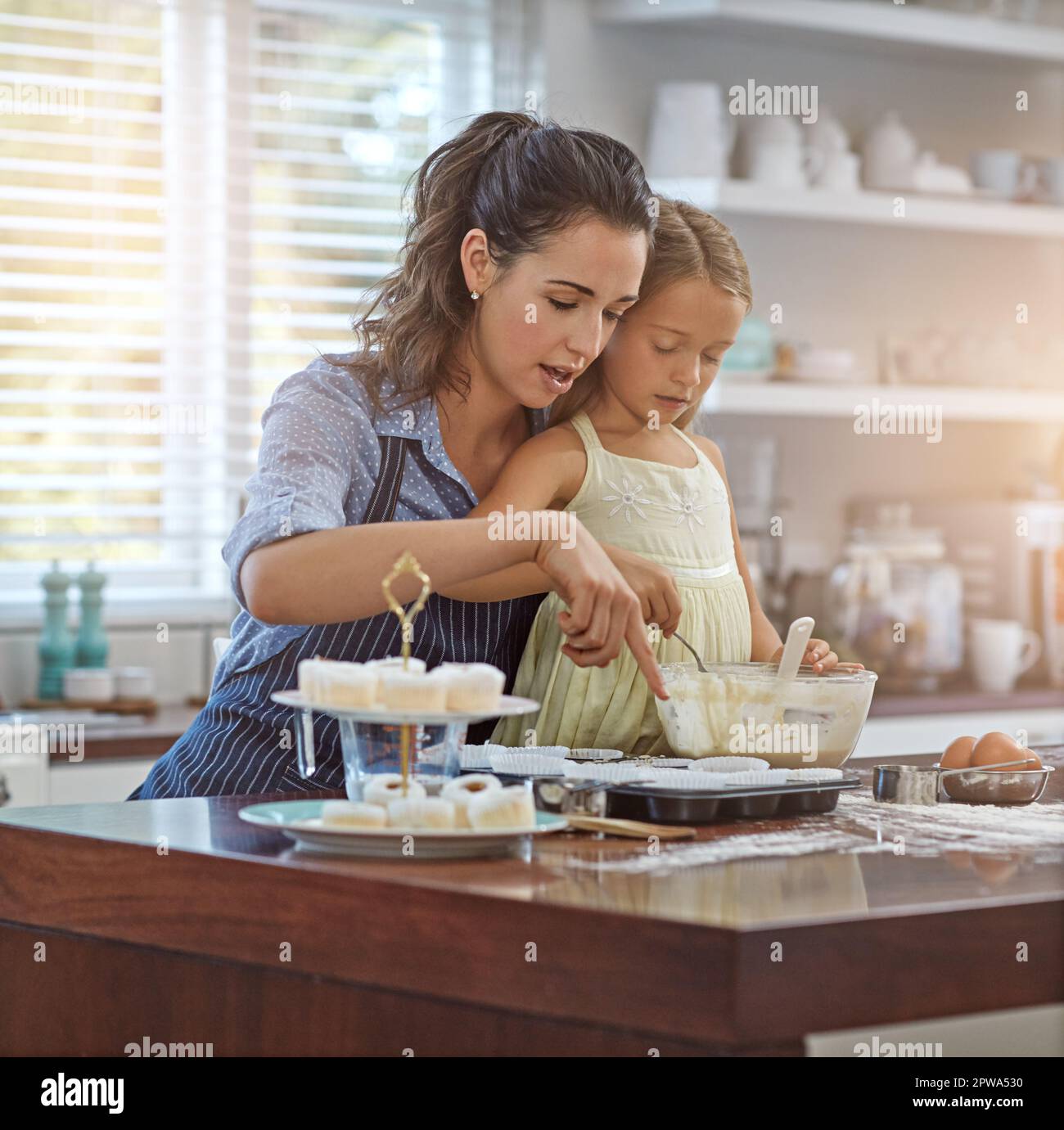Making something sweet. a mother and her daughter baking in the kitchen ...
