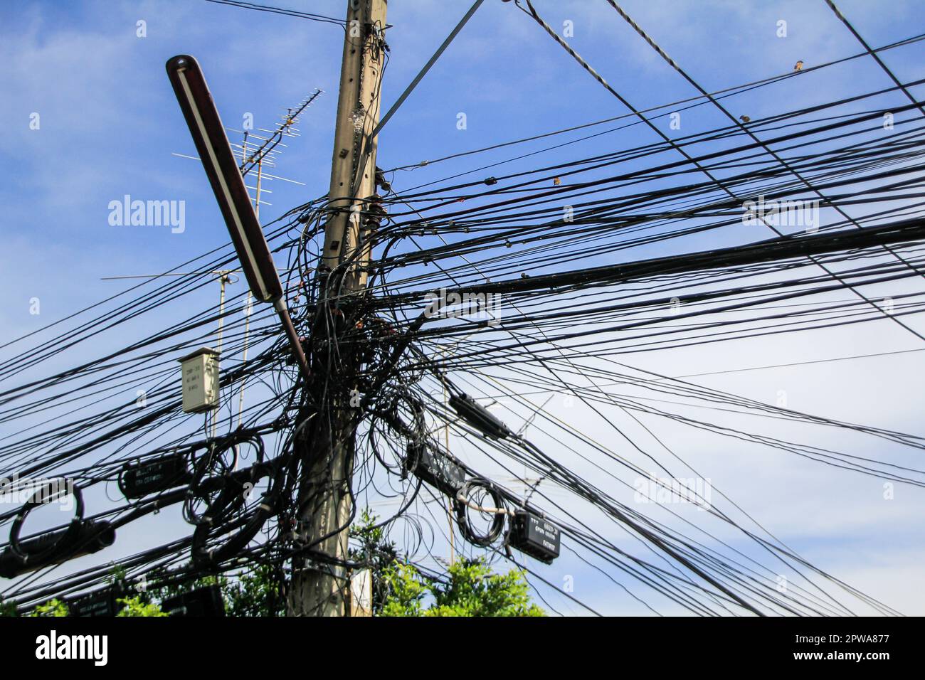 Tangled bundles of overhead wires. Electricity system on the streets of ...