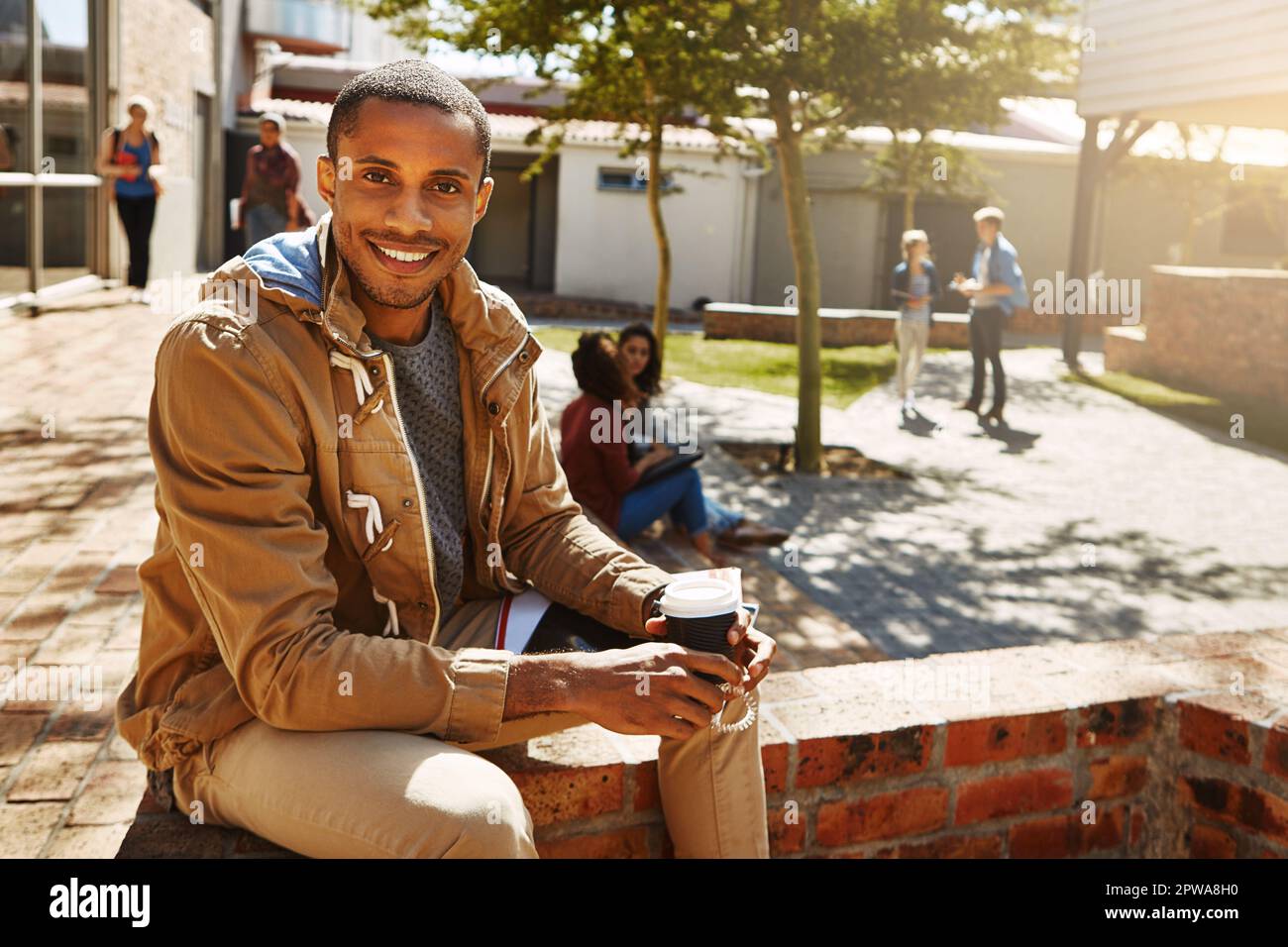 Have a coffee and study hard. Portrait of a young student sitting on ...