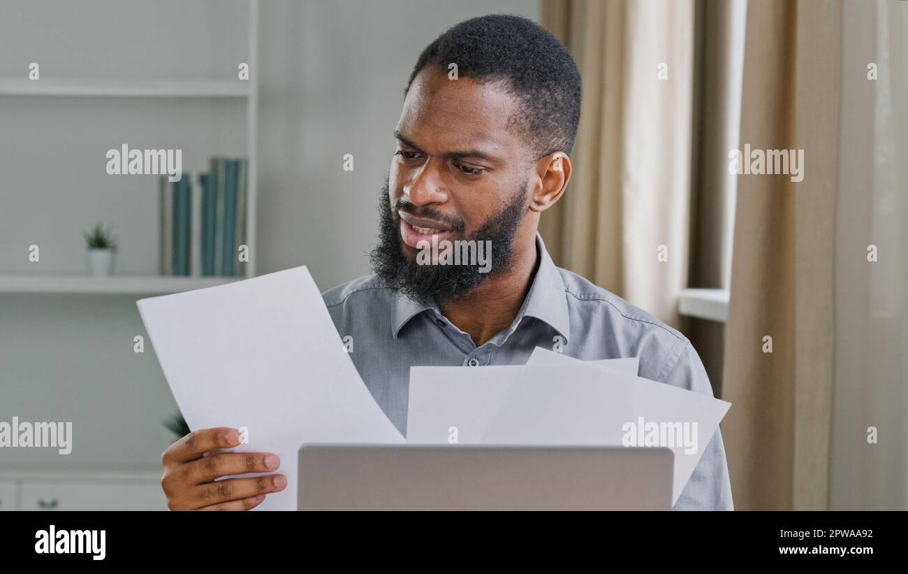 Overworked millennial ethnic male office worker stressed by paperwork ...